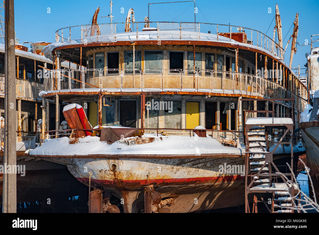 Old rusty ferries located near snowy shore of harbor against cloudless ...