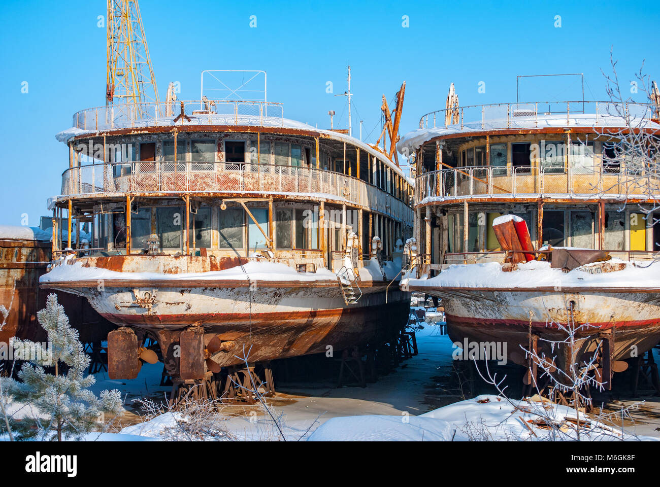 Old rusty ferries located near snowy shore of harbor against cloudless ...