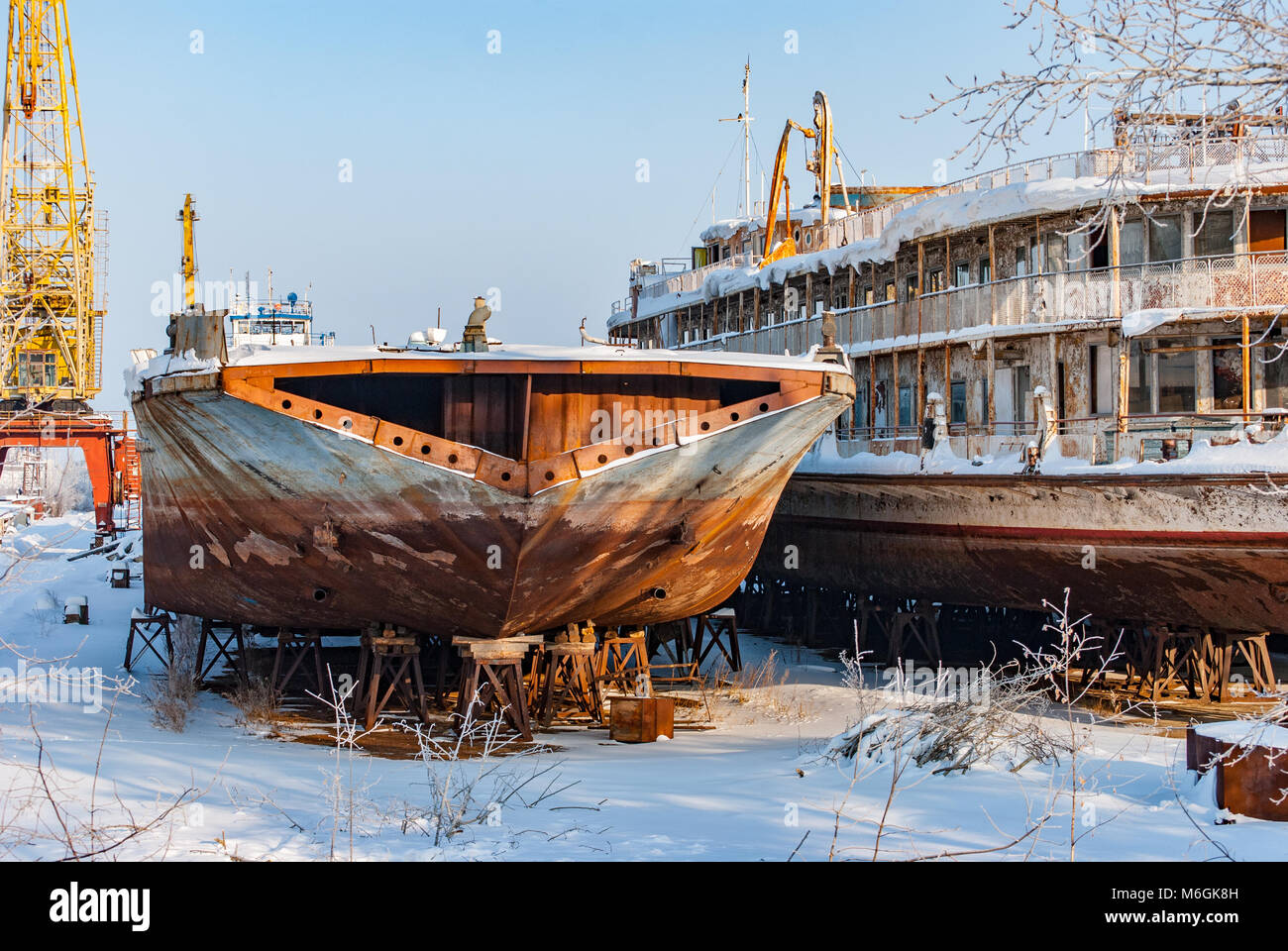 Old rusty ferries located near snowy shore of harbor against cloudless ...