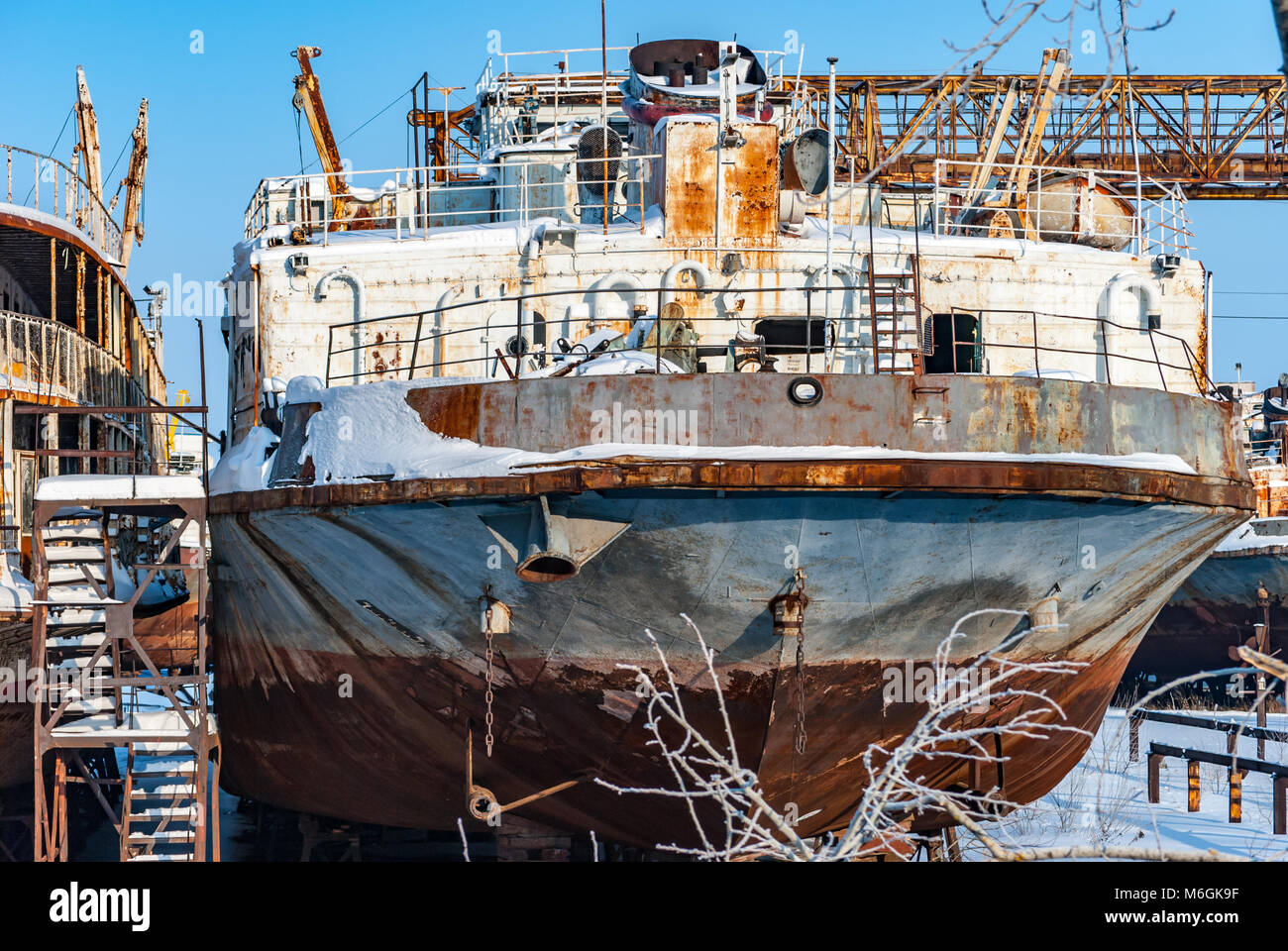 Old rusty ferries located near snowy shore of harbor against cloudless ...
