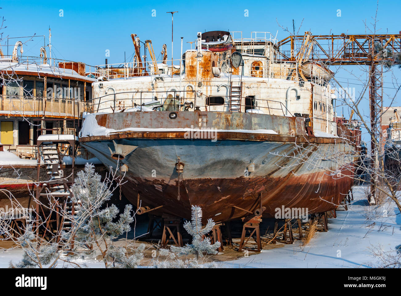 Old rusty ferries located near snowy shore of harbor against cloudless ...