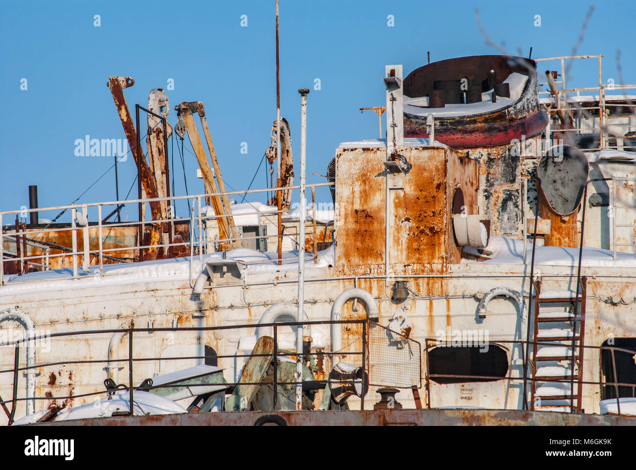 Old rusty ferries located near snowy shore of harbor against cloudless ...