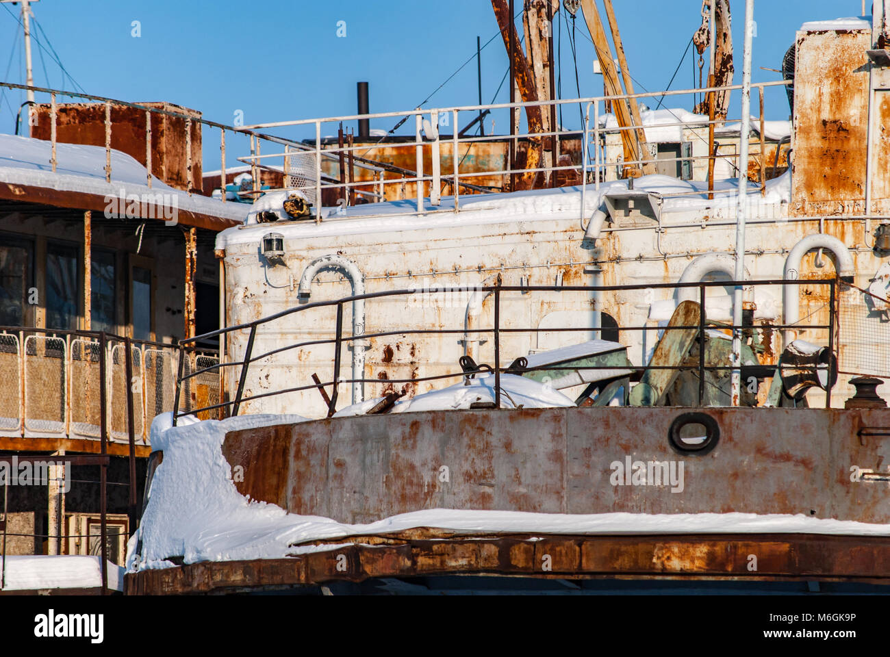Old rusty ferries located near snowy shore of harbor against cloudless ...