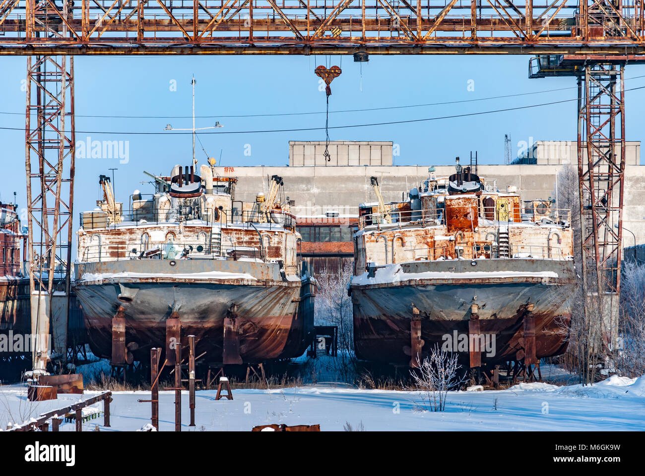 Old rusty ferries located near snowy shore of harbor against cloudless ...