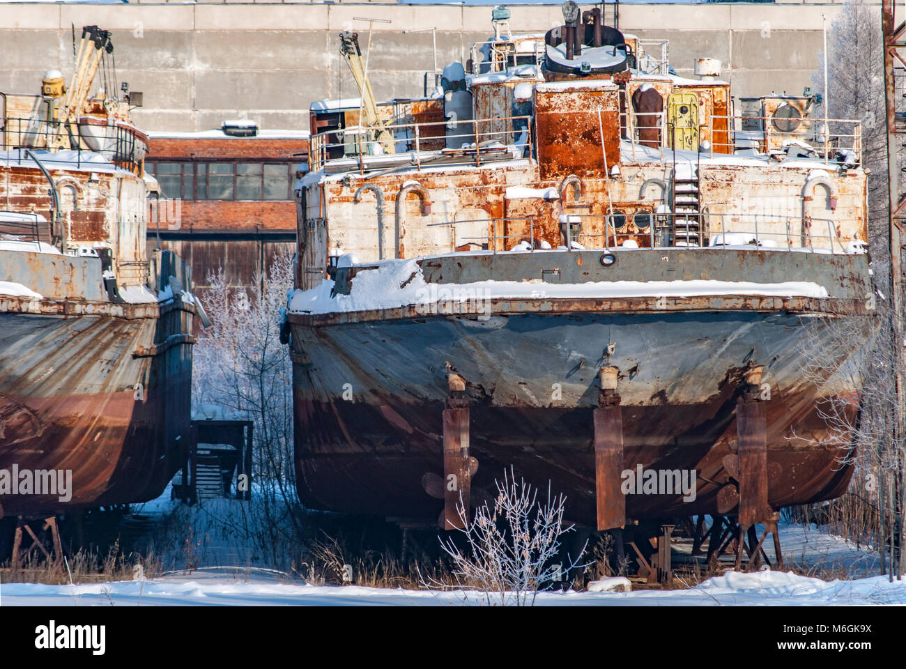 Old rusty ferries located near snowy shore of harbor against cloudless ...