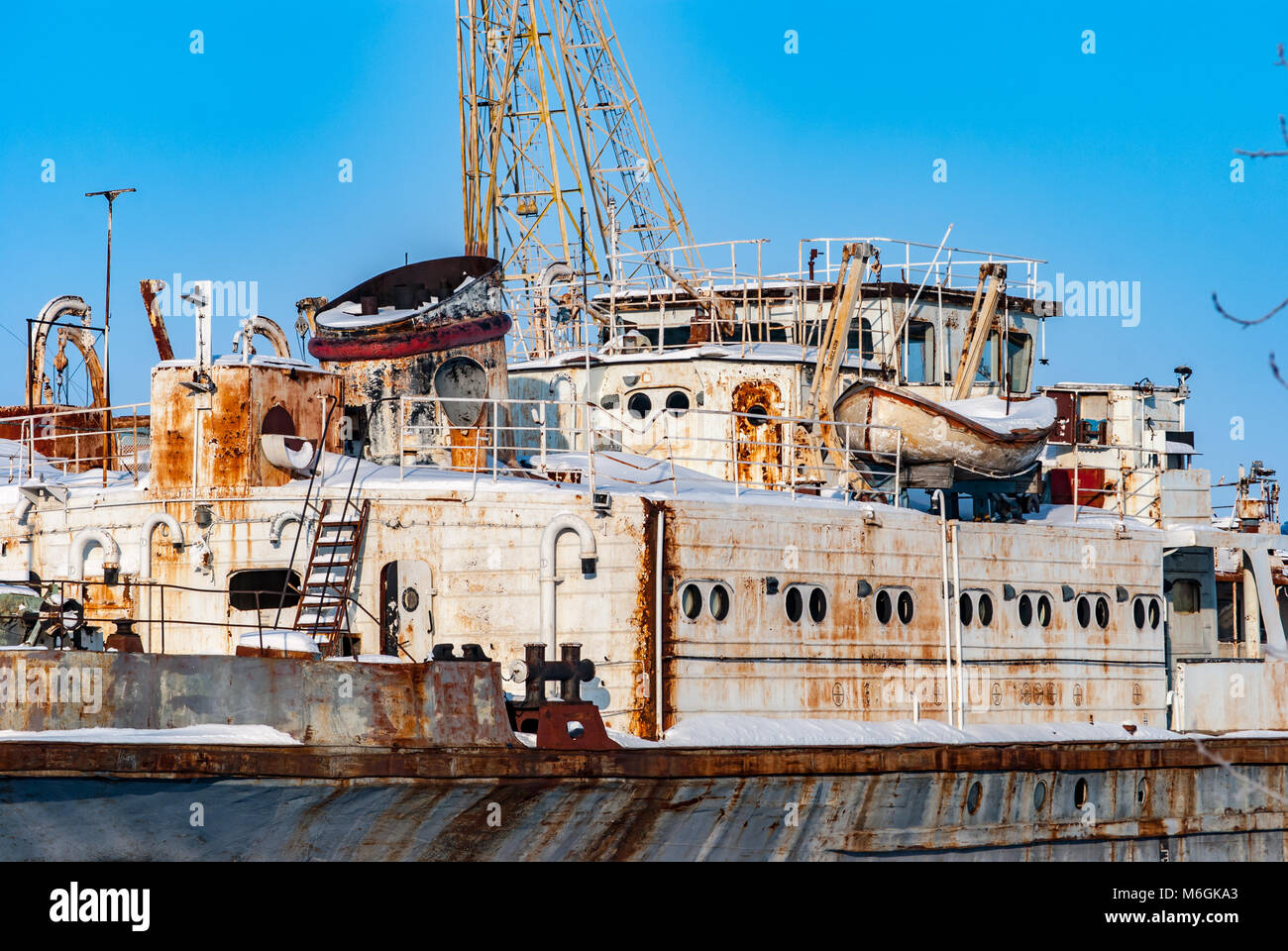 Old rusty ferries located near snowy shore of harbor against cloudless ...