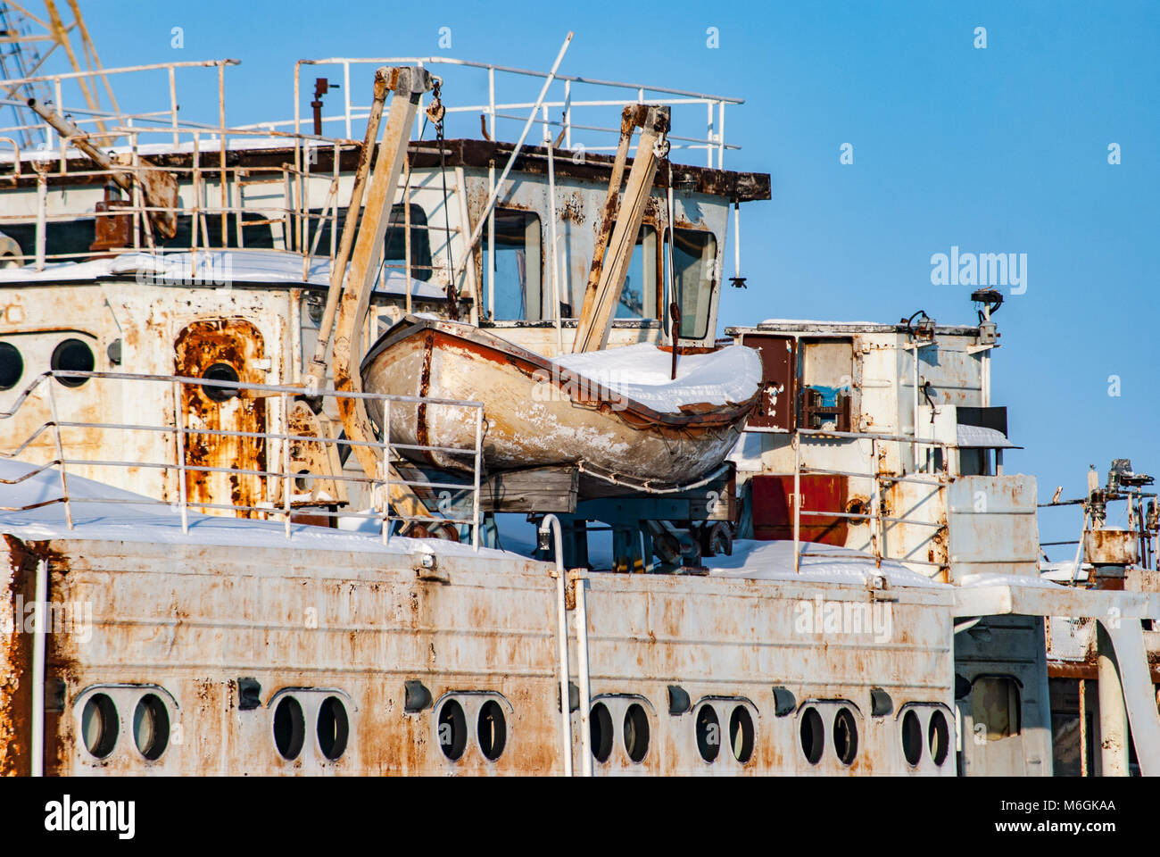 Old rusty ferries located near snowy shore of harbor against cloudless ...