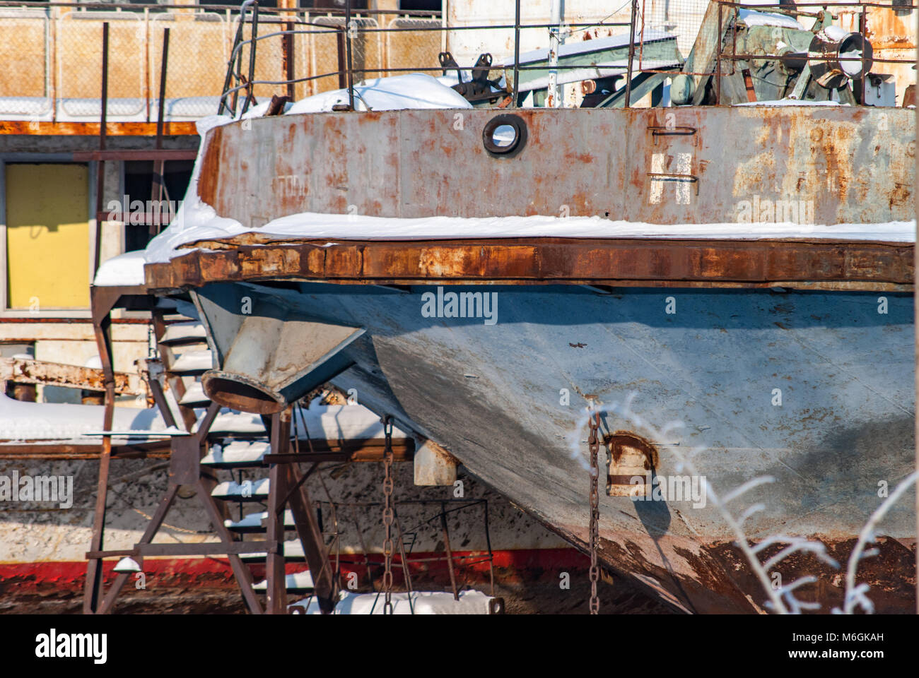 Old rusty ferries located near snowy shore of harbor against cloudless ...