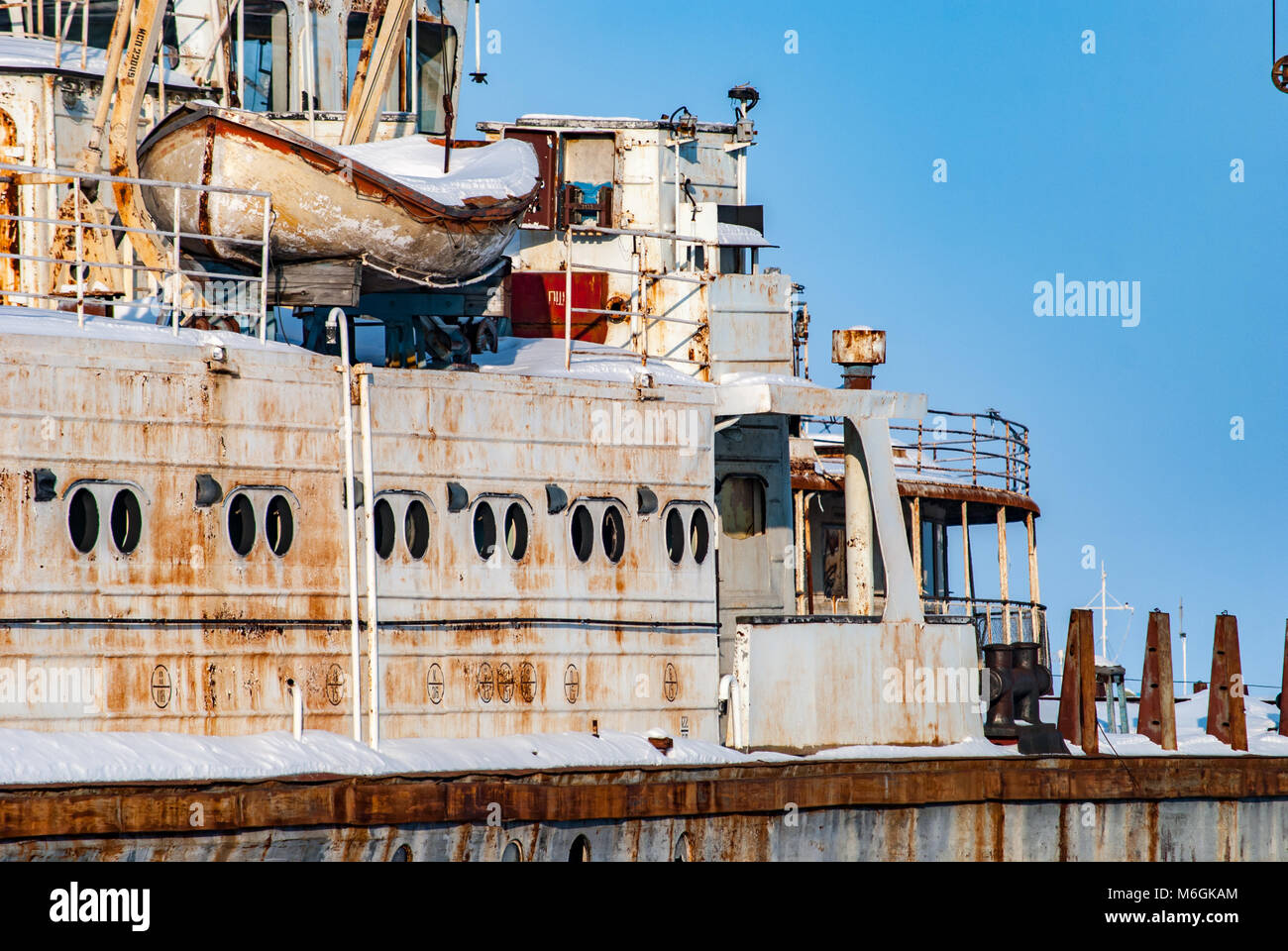 Old rusty ferries located near snowy shore of harbor against cloudless ...