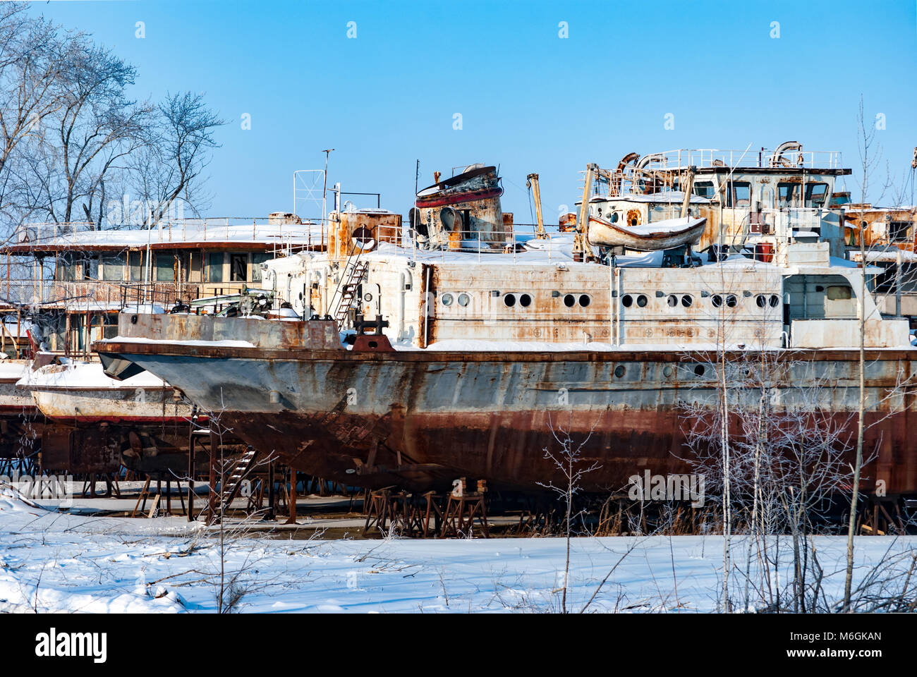 Old rusty ferries located near snowy shore of harbor against cloudless ...
