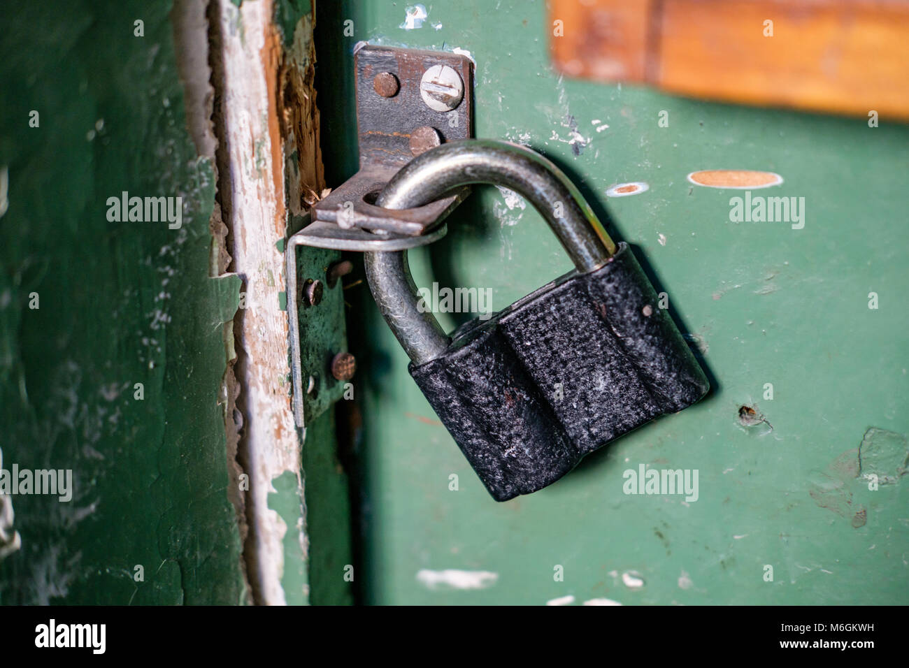 New padlock on the old green door in the entrance of an old apartment ...