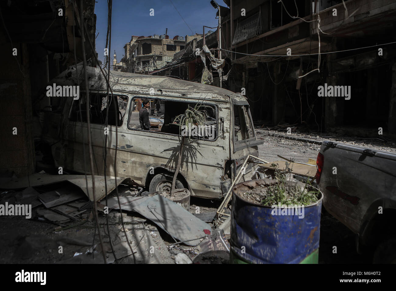 A Syrian man stands amidst houses damaged by aistrikes in the rebel ...
