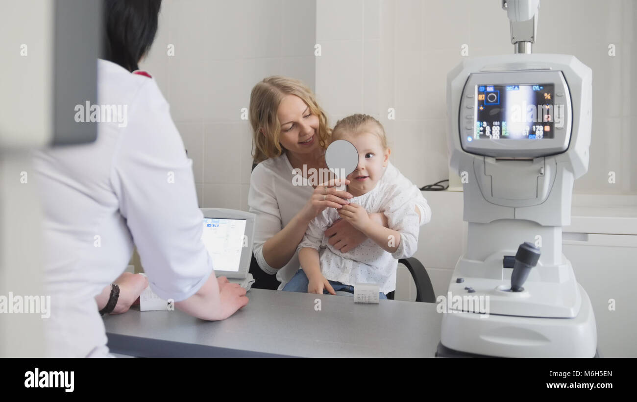 Optometrist checks child's eyesight - mother and child in ...