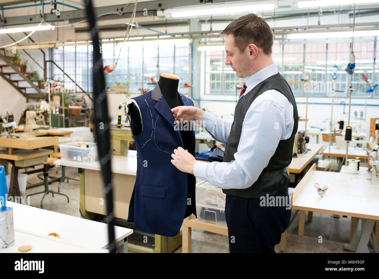Tailor working over jacket hanging on mannequin in workshop Stock Photo ...
