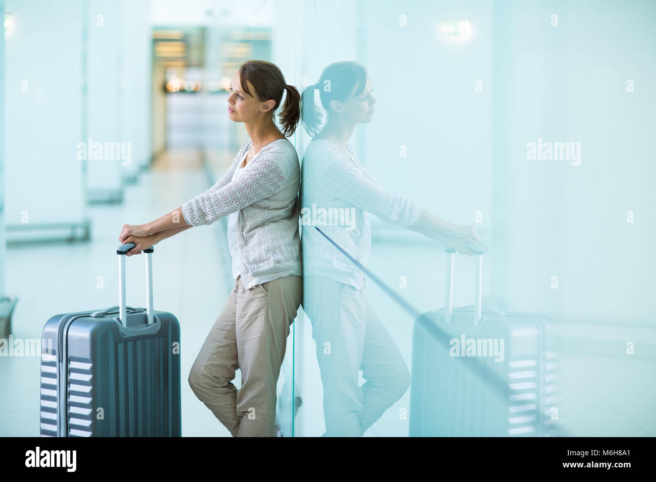 Young female passenger at the airport, waiting for her delayed flight ...