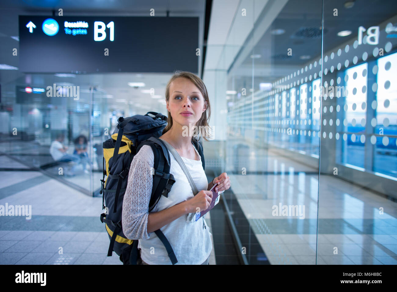 Young female passenger at the airport, waiting for her delayed flight ...