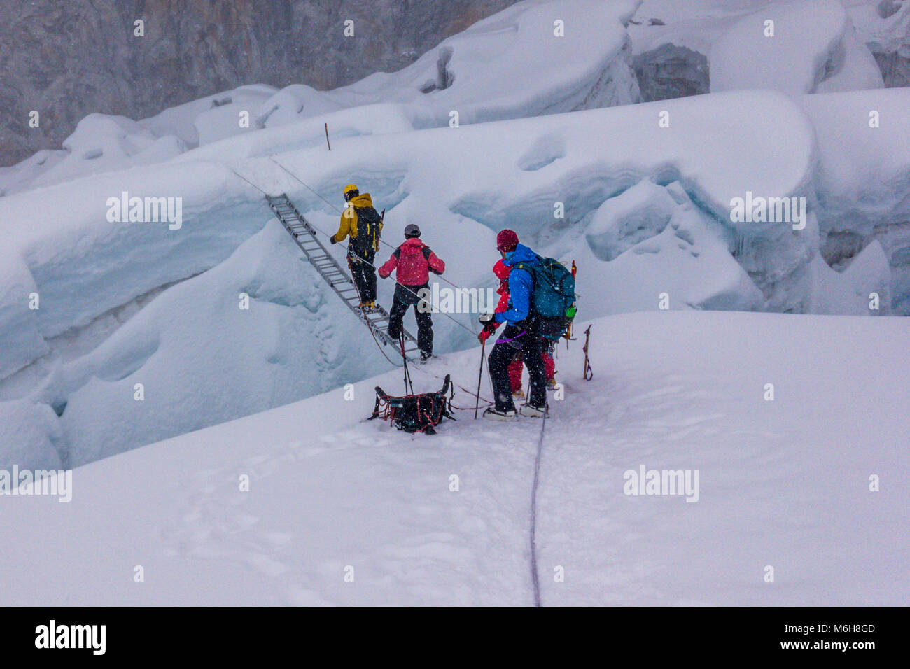 A group of climbers crossing a crevasse over a ladder, Island Peak ...