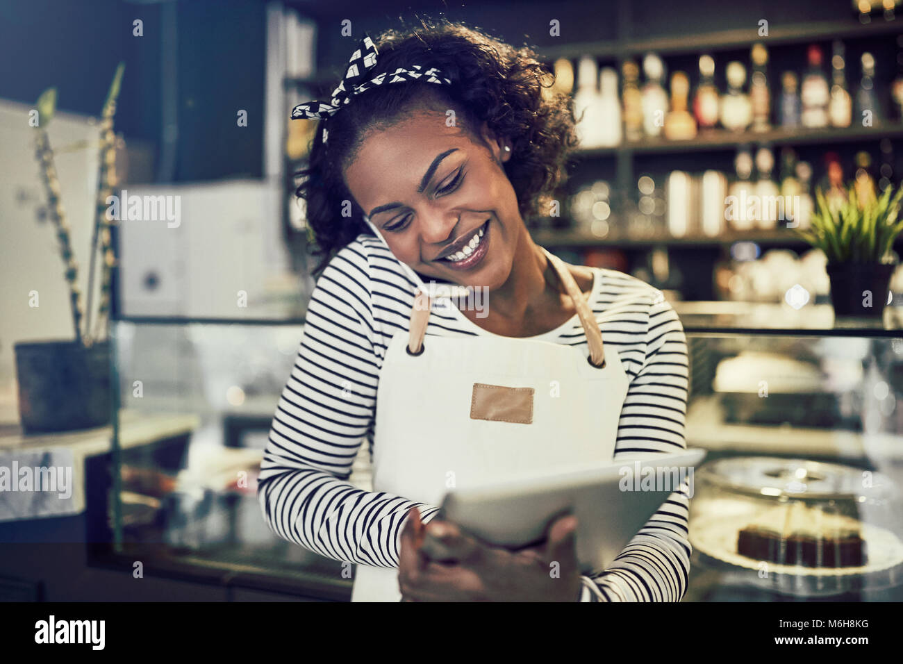 Smiling young African entrepreneur standing at the counter of her cafe ... Smiling young African entrepreneur standing at the counter of her cafe ...