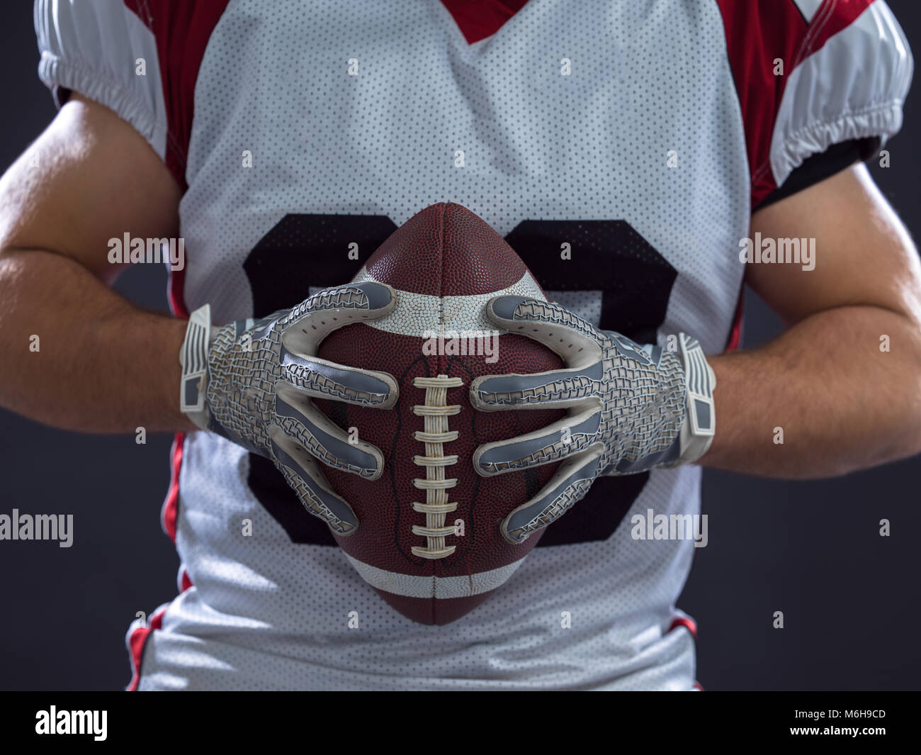 Portrait of a strong muscular American Football Player isolated on gray ...