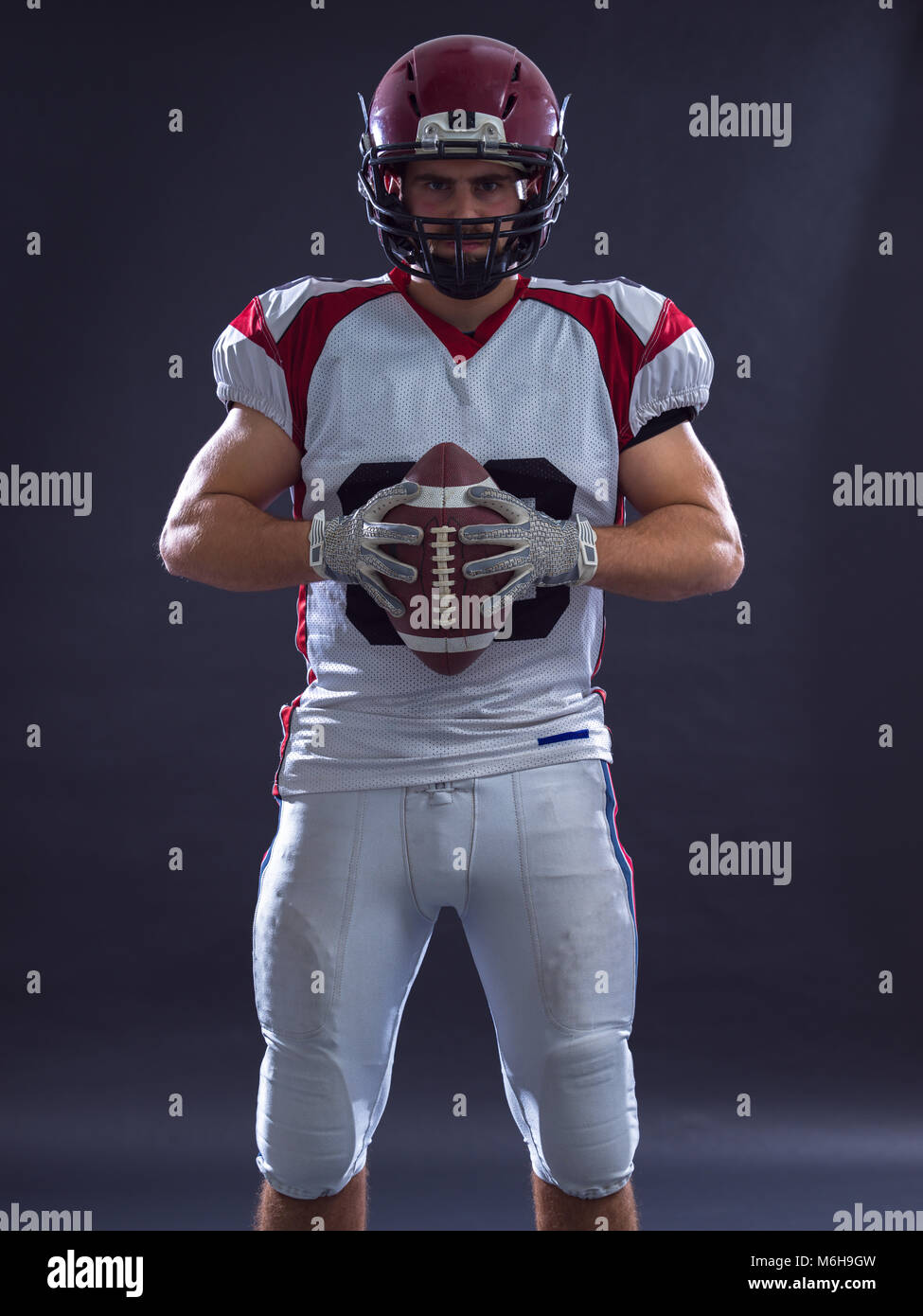 Portrait of a strong muscular American Football Player isolated on gray ...