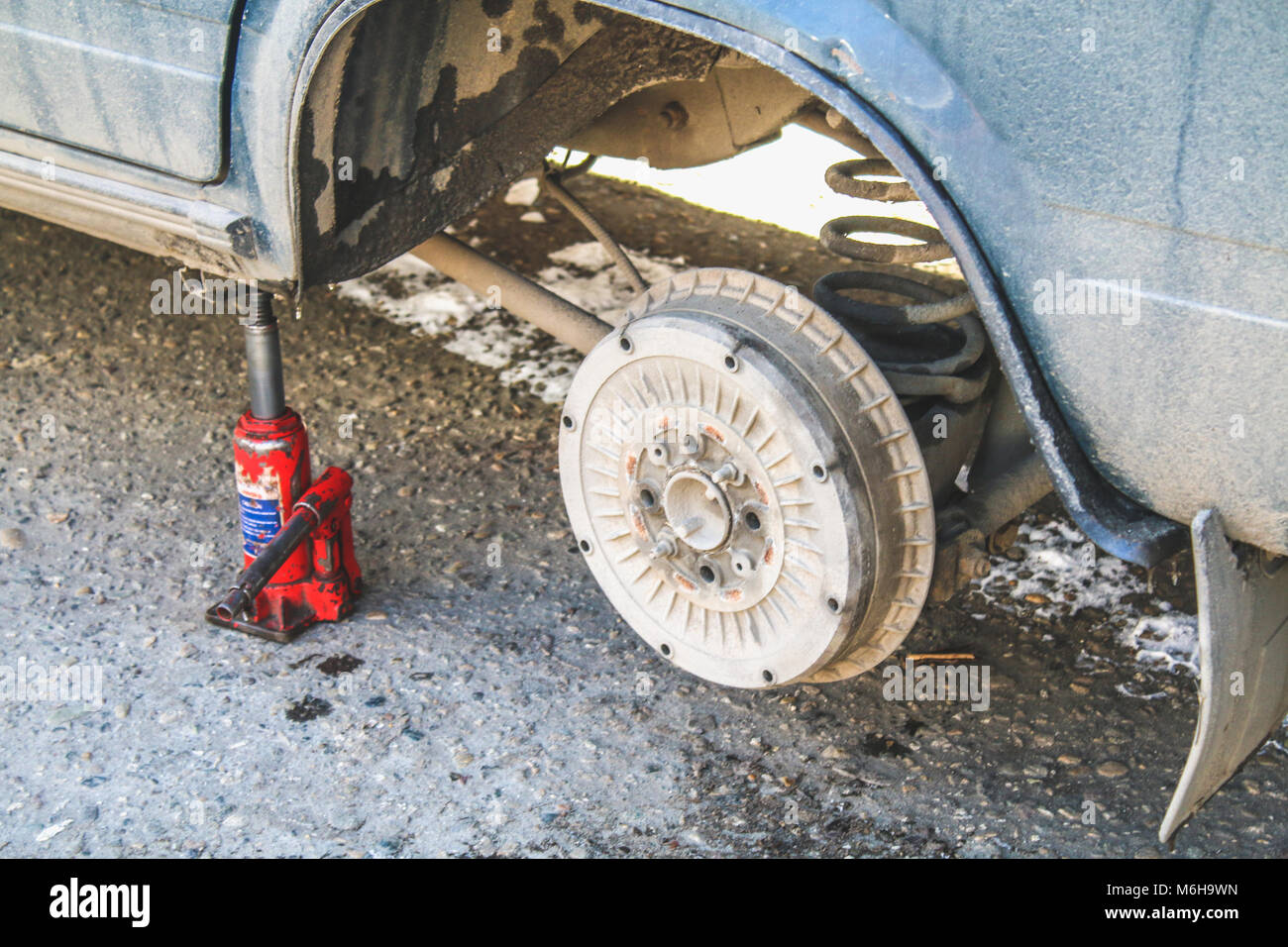 A red jack lifts the car to replace the punctured wheel Stock Photo - Alamy
