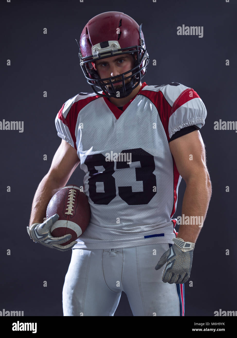 Portrait of a strong muscular American Football Player isolated on gray ...