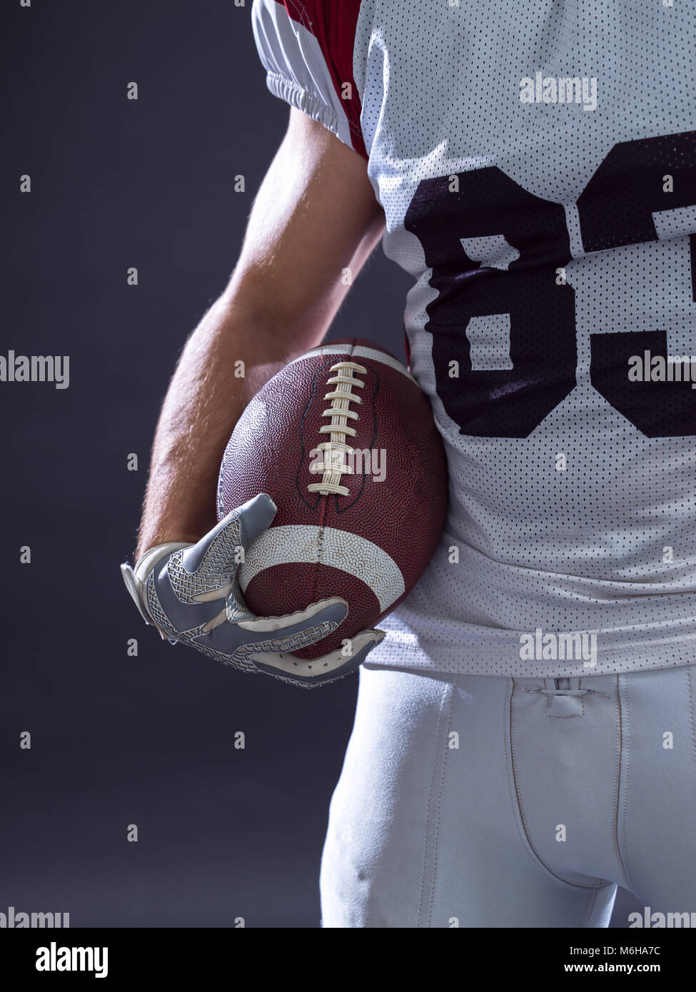 Portrait of a strong muscular American Football Player isolated on gray ...