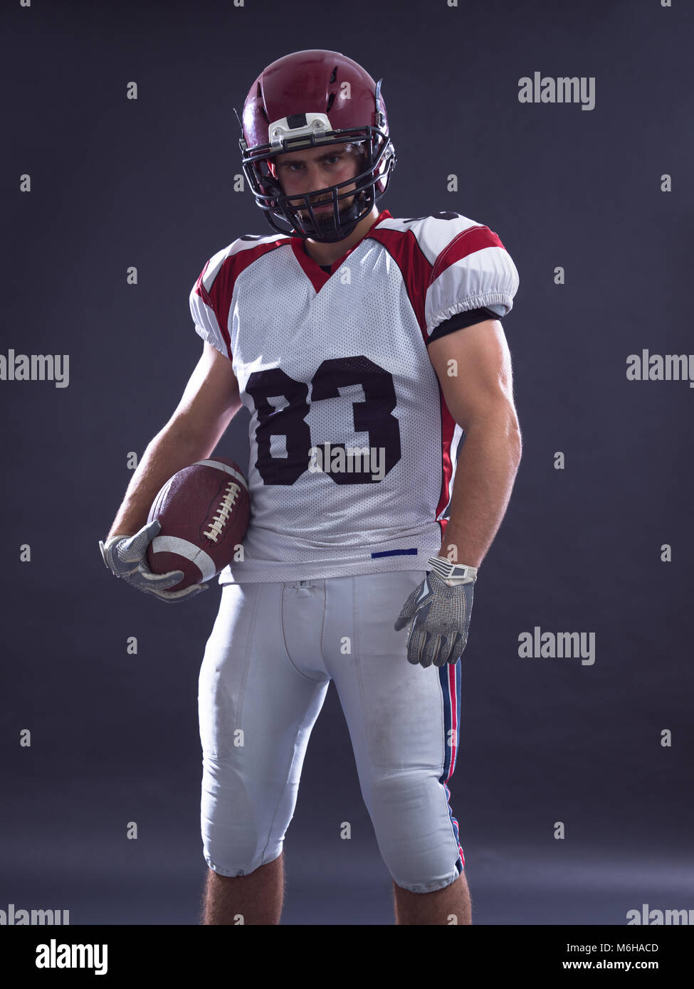 Portrait of a strong muscular American Football Player isolated on gray ...