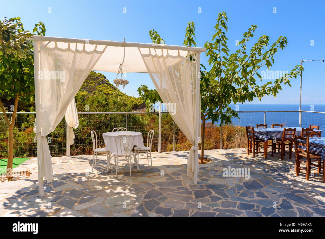 Tables with chairs on terrace of coastal restaurant in Porto Schiza on ...