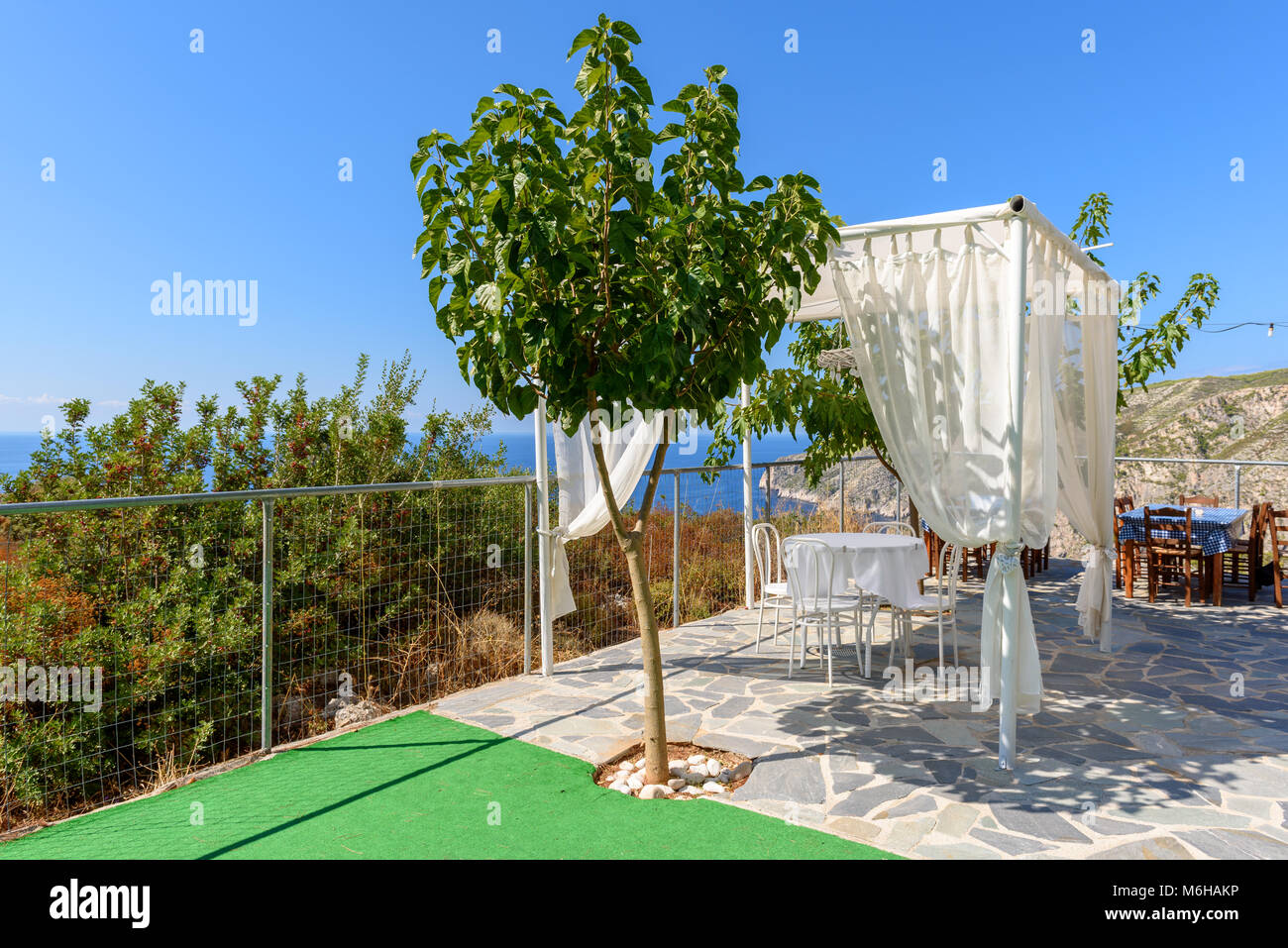 Tables with chairs on terrace of coastal restaurant in Porto Schiza on ...