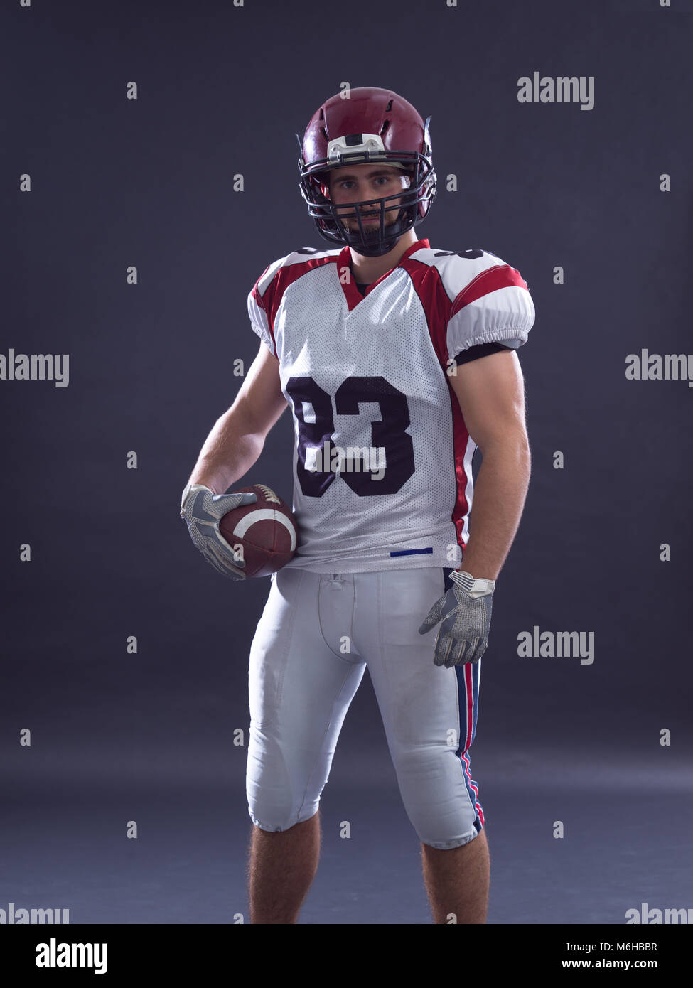 Portrait of a strong muscular American Football Player isolated on gray ...