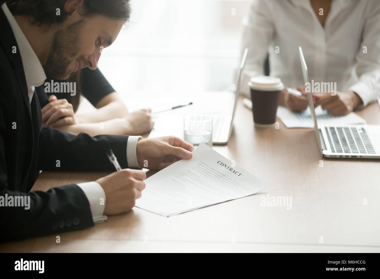 Satisfied smiling businessman signing business contract with div Stock ...