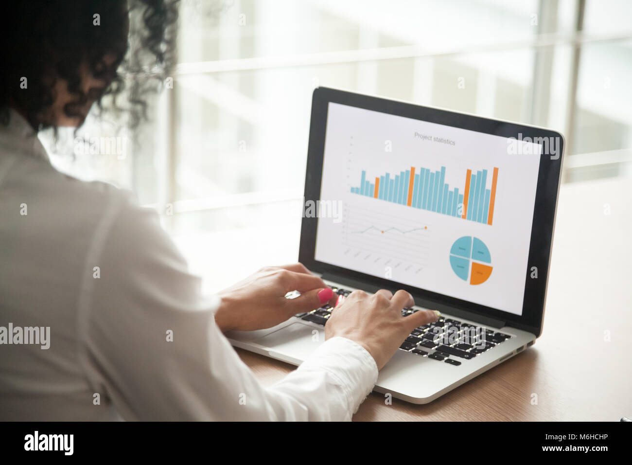 African businesswoman analyzing project statistics on laptop scr Stock ...