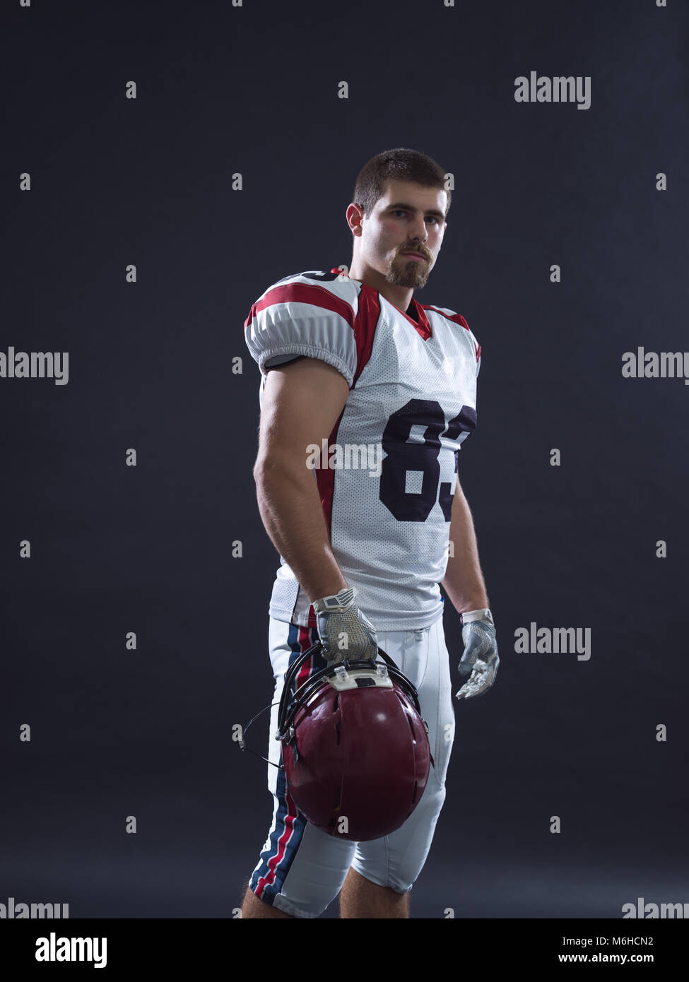 Portrait of a strong muscular American Football Player isolated on gray ...