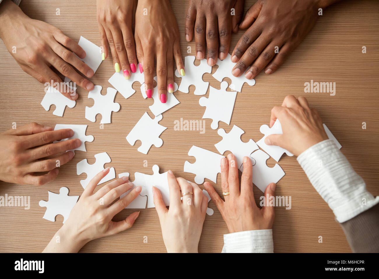 Hands of diverse people assembling jigsaw puzzle together, top v Stock ...