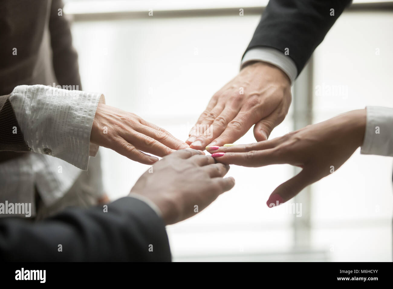 Hands of four diverse partners join together, close up view Stock Photo ...