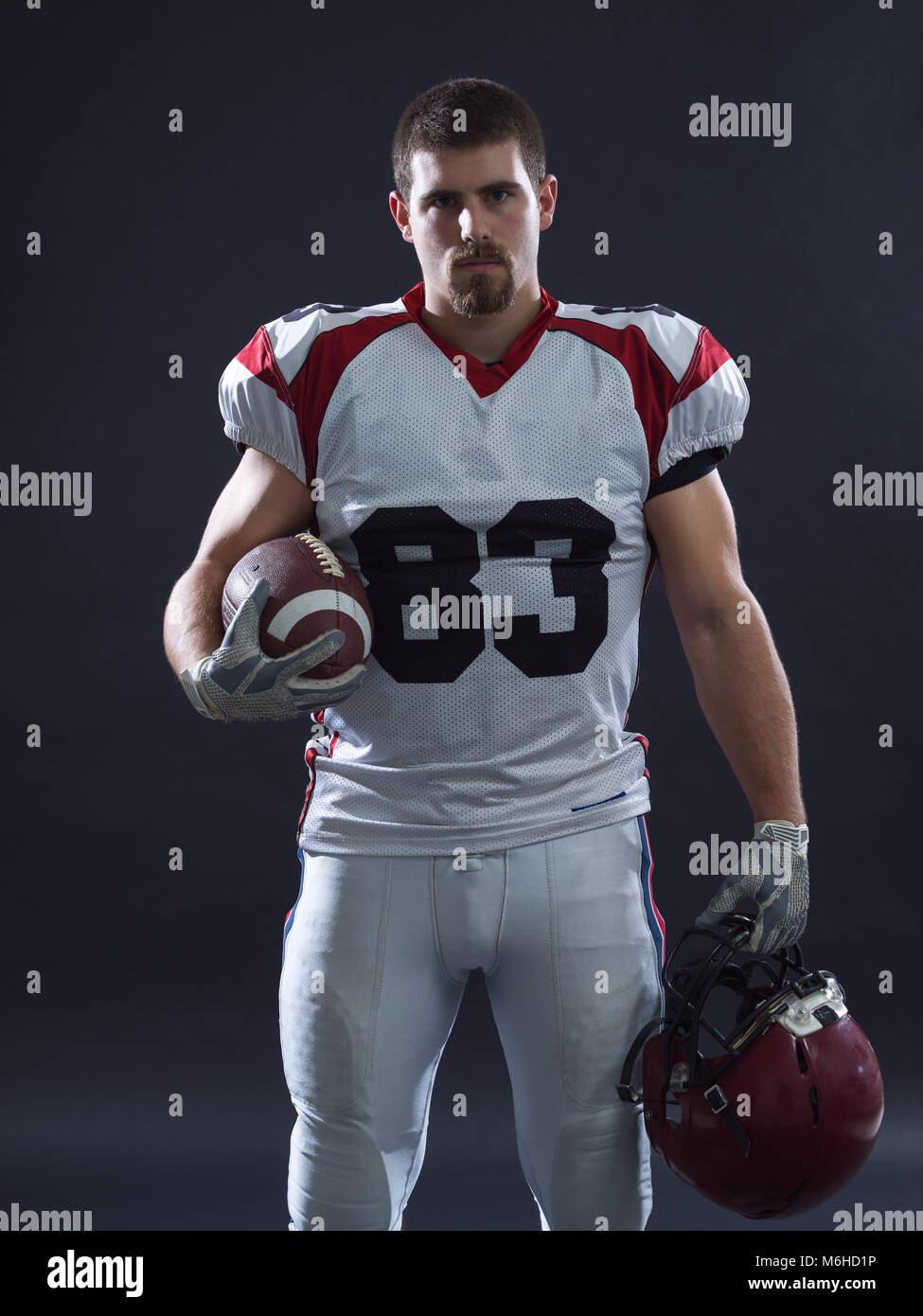 Portrait of a strong muscular American Football Player isolated on gray ...
