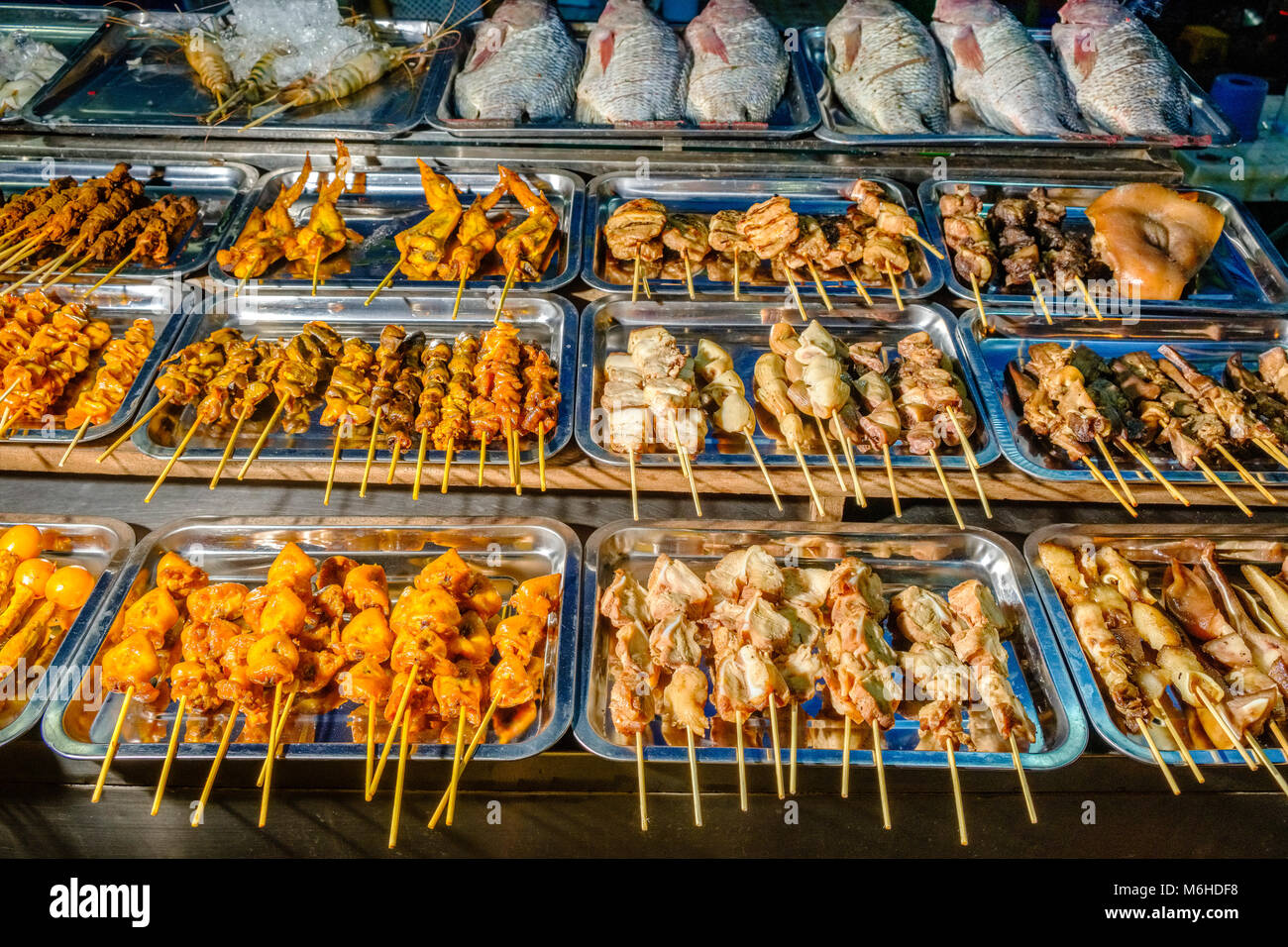 Fried chicken meat on skewers and fresh fish are offered to eat in ...