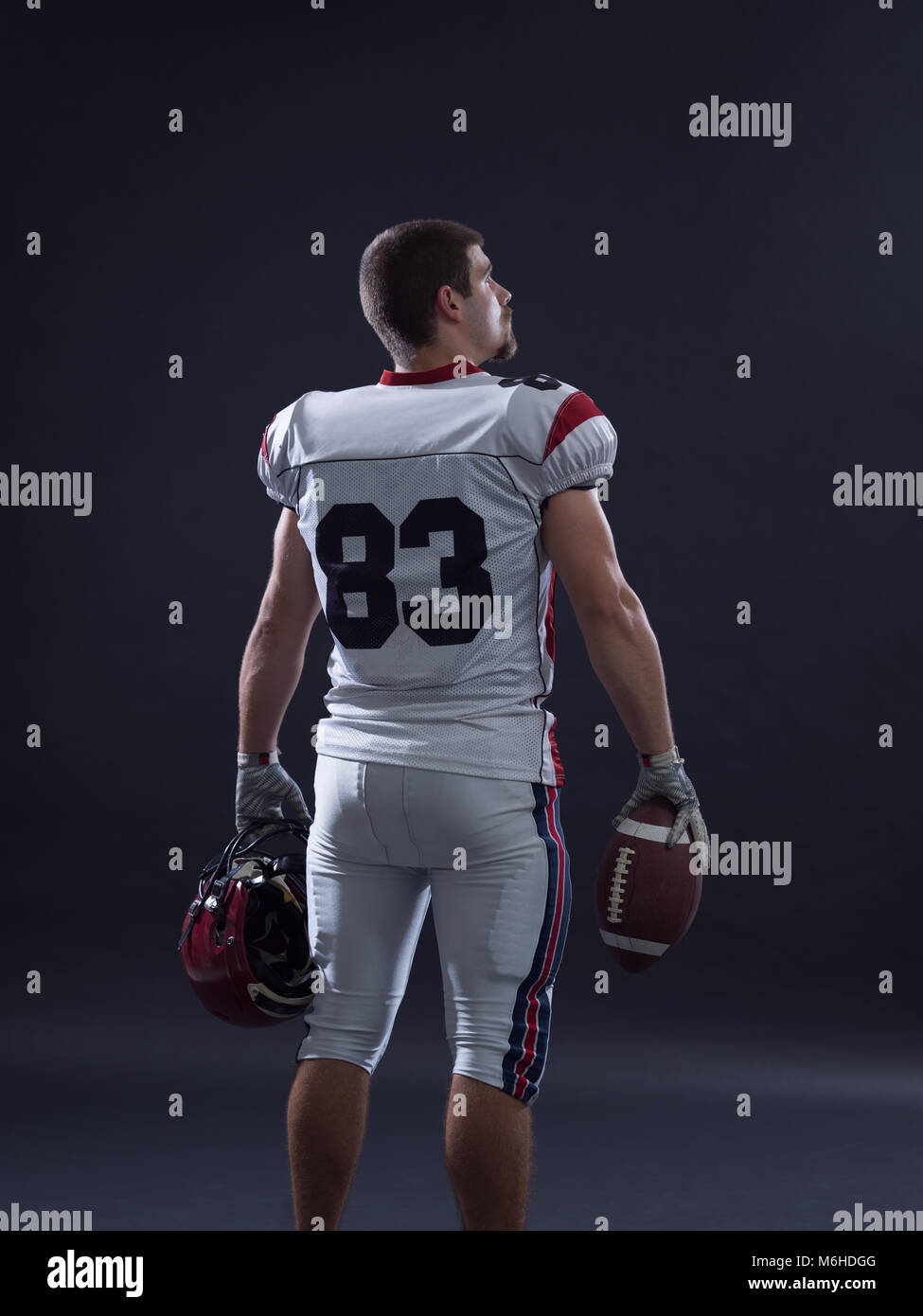 Portrait of a strong muscular American Football Player isolated on gray ...