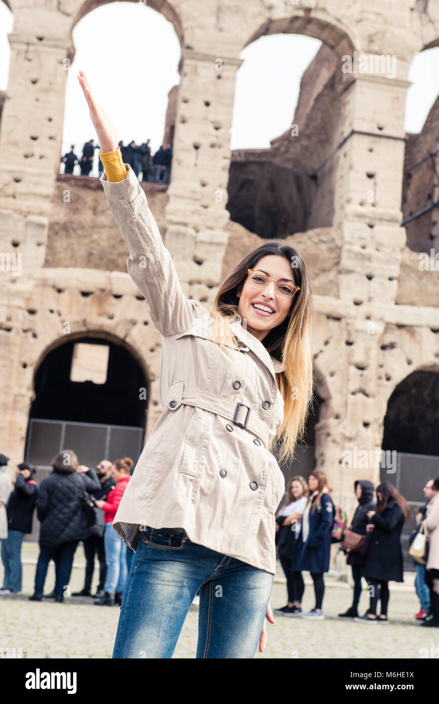 Young pretty tourist woman smiling and pointing out, colosseum monument ...
