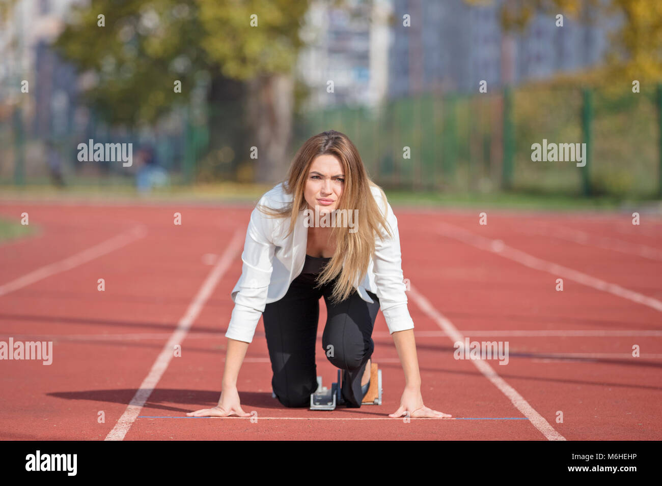 business woman in start position ready to run and sprint on athletics ...