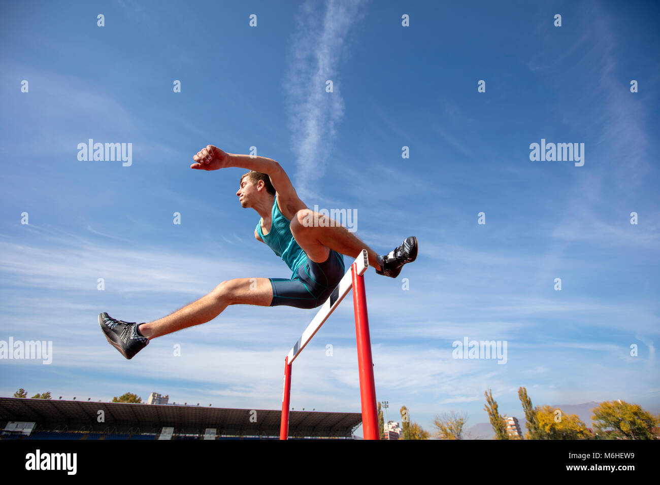 Low angle view of determined male athlete jumping over a hurdles Stock ...