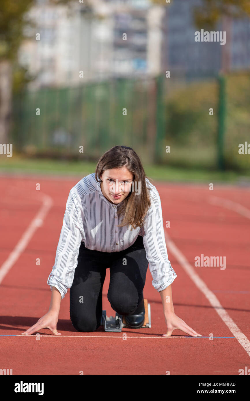 business woman in start position ready to run and sprint on athletics ...