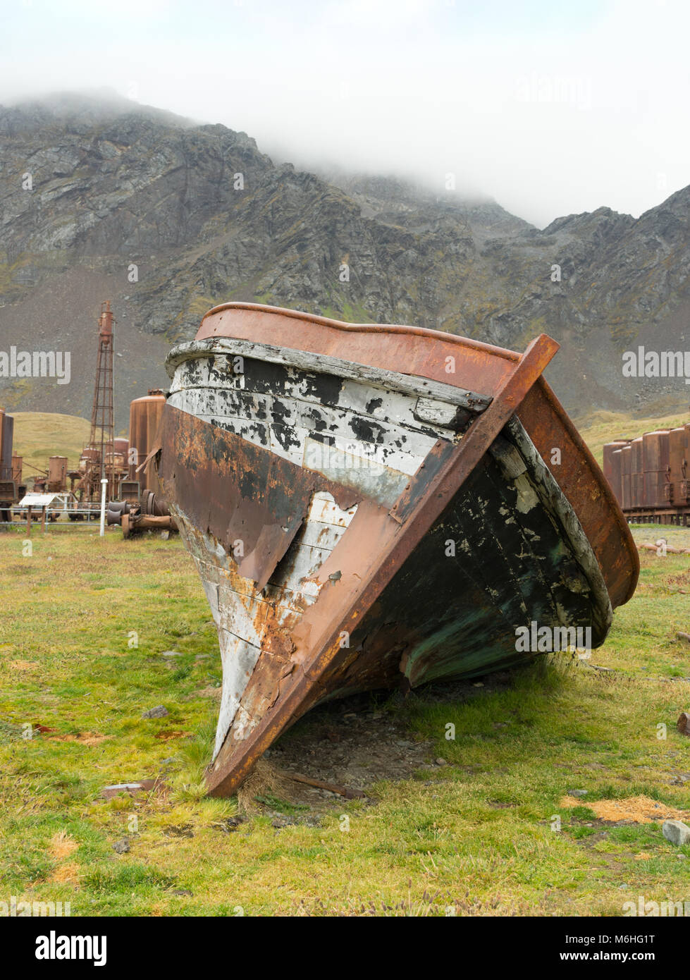 A damaged boat with rusted sheet metal coming off exposing the wood ...