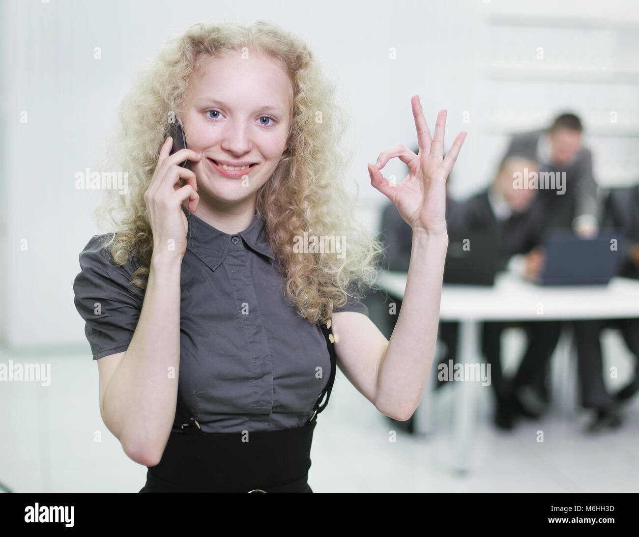 young female assistant showing OK sign,standing in the office Stock ...