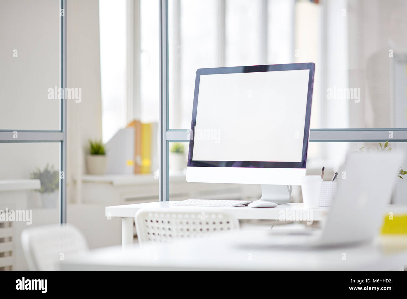 Empty office room with glass partitions and computer with blank screen ...
