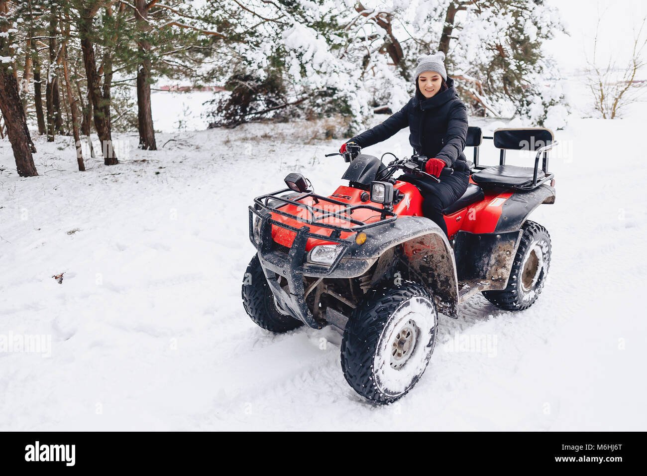 young girl on a motorcycle rides in snow-covered pine forest winters ...
