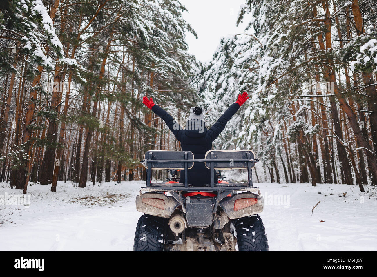 young girl on a motorcycle rides in snow-covered pine forest winters ...