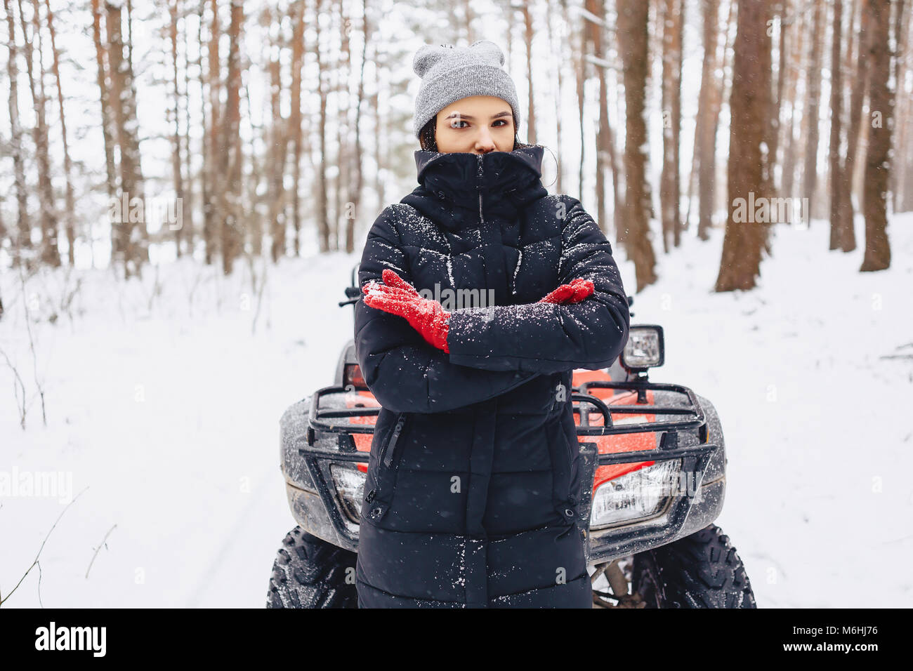 young girl on a motorcycle rides in snow-covered pine forest winters ...