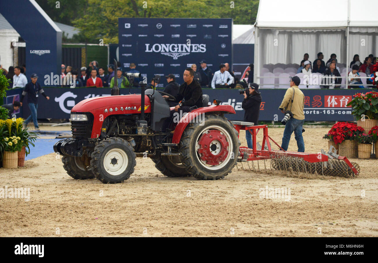 Staff use a tractor to rake the sand surface at the FEI jumping event ...